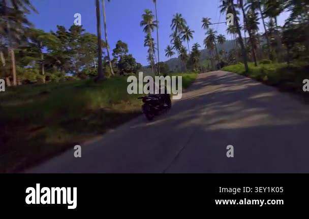 Rear View of Young Woman Riding Scooter Along Empty Tropical Road ...