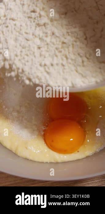 Vertical video. Flour Being Poured Over Egg And Sugar Mixture In Large ...