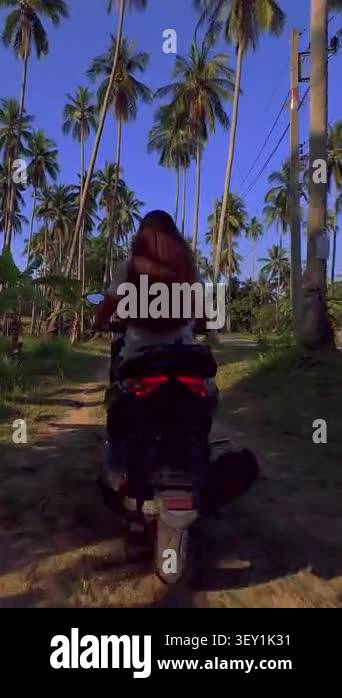 Vertical video. Rear View of Young Woman Riding Scooter on Dirt Path ...