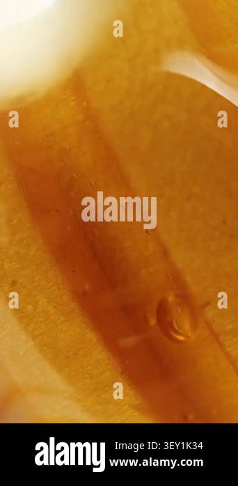 Vertical video. Golden Honey Drop Hitting Lens And Spreading Across ...