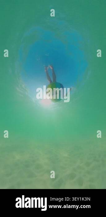 Vertical video. Underwater View Woman Floating In Inflatable Ring Above ...