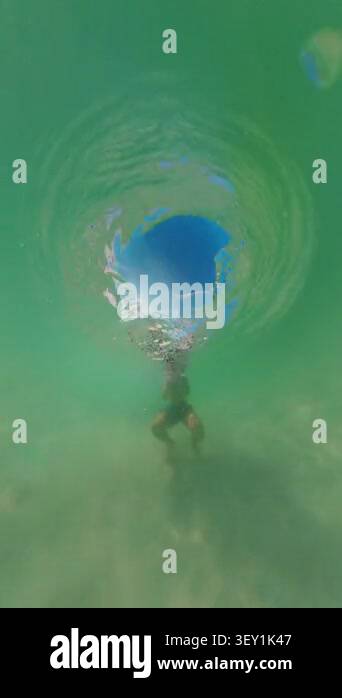 Vertical video. Underwater View Looking Up At Surface Opening With ...