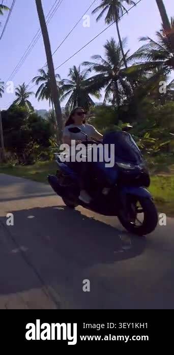 Vertical video. Low Angle Front View of Young Woman Riding Scooter With ...
