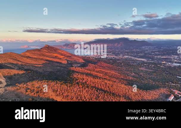 Twilight aerial ridge with glowing ridgeline and bay, city lights faint ...