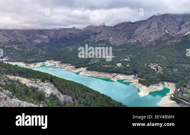 Expansive turquoise reservoir framed by mountains, cinematic aerial ...