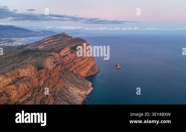 Aerial red cliff under pastel sky at dusk, layered rock strata ...