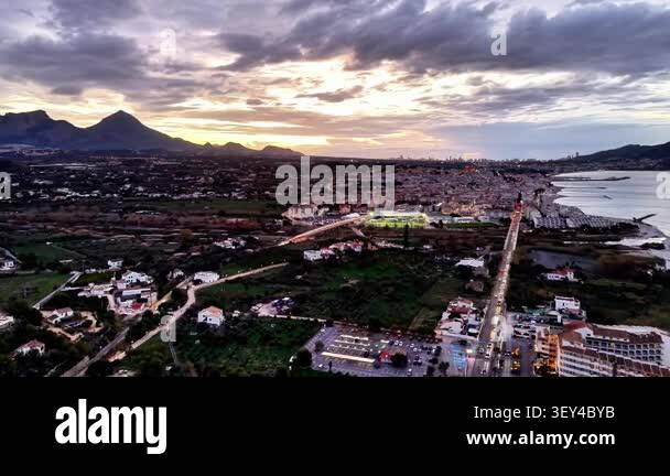Sunset aerial view coastal town, showing mountain silhouette, winding ...