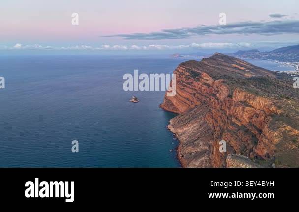 Aerial cliff and islet framed by pastel dusk, layered rock textures and ...