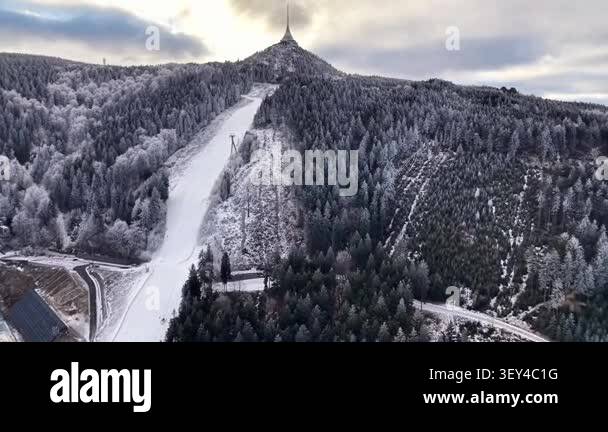 Snow covered ski slope on mountain ridge with frosted trees and steep ...