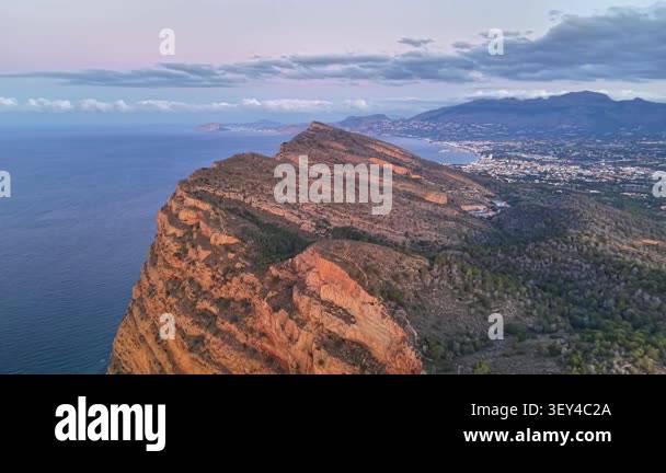 Aerial cliff promontory at twilight with pastel sky and calm ocean ...