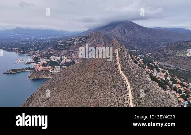 Aerial promenade along coastal ridge with clear path, houses descending ...