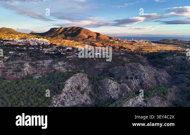 Sunset hills and village rooftops bathed in golden light, cinematic ...