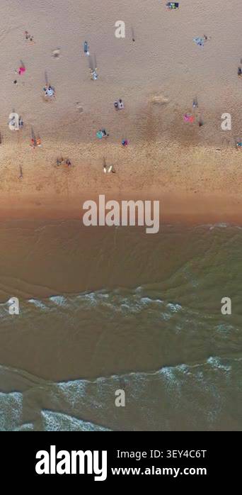 Top-down drone view of people walking on a sandy beach near shallow ...