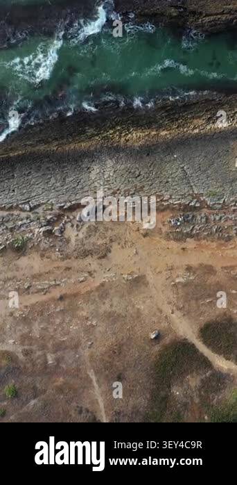 Top-down drone view of ocean water meeting a rocky sandy beach with ...