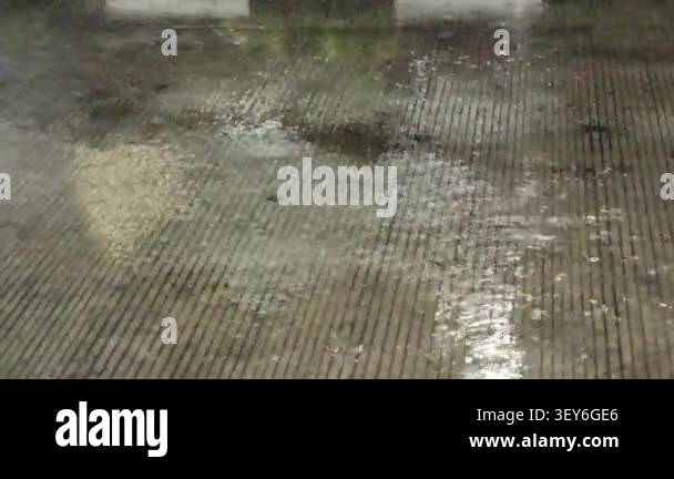 Raindrops falling on a textured concrete surface, creating ripples and ...