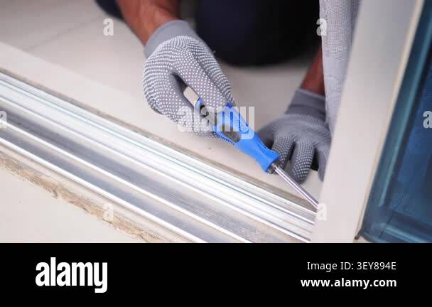 A person is repairing a sliding door track using a screwdriver Stock ...