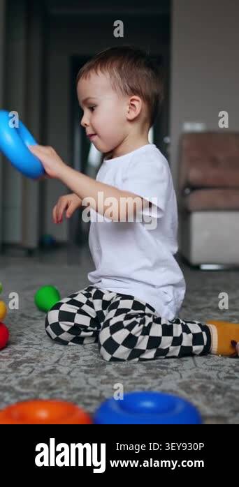 Two-year old toddler plays on the floor with his toys. Lovely baby ...