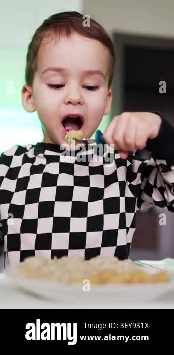 Lovely boy wearing checkered shirt eats from a fork. Two-year-old ...