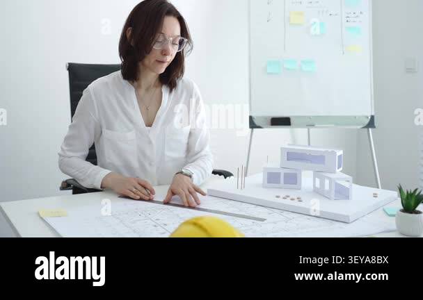 Female architect in office carefully drawing blueprint for new ...