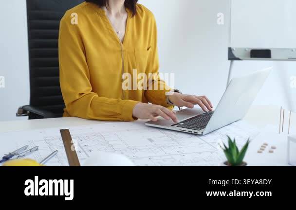 Woman architect actively working on a laptop computer, surrounded by ...