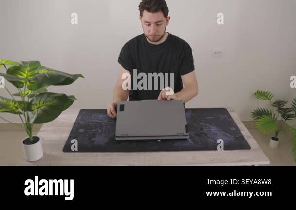 A male freelancer opens his personal computer and begins typing at a ...