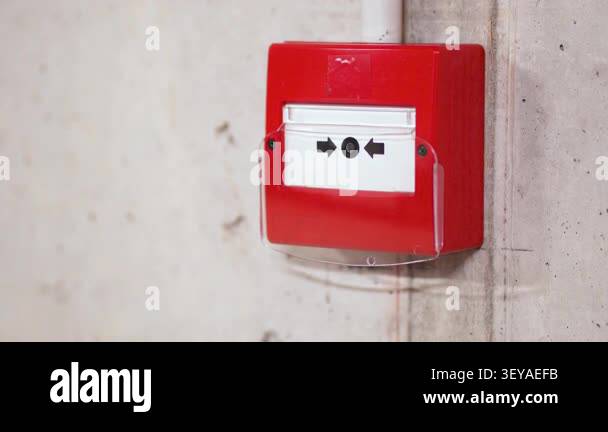 Close up of male hand pointing at red fire alarm switch on concrete ...