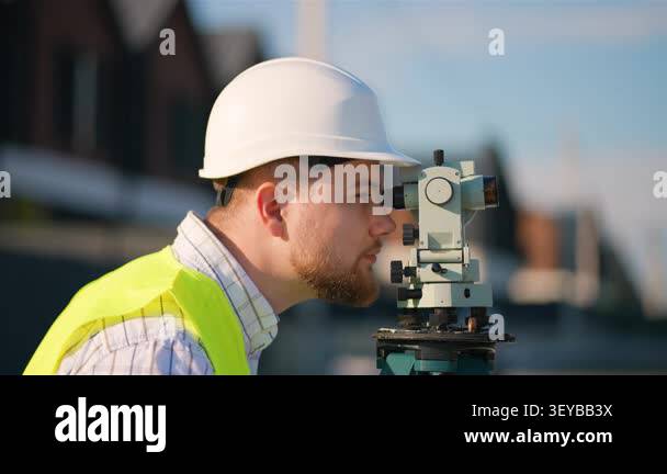Professional surveyor working with a theodolite, measuring levels on a ...