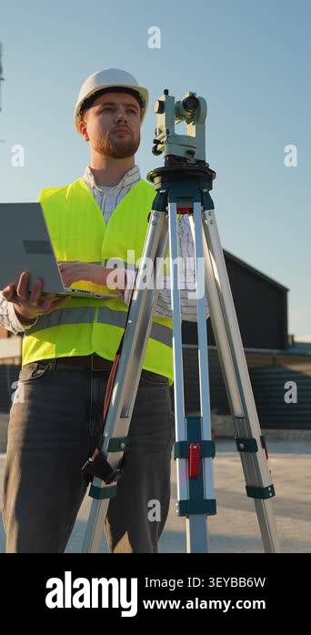 Professional surveyor working with a theodolite and a laptop at a ...