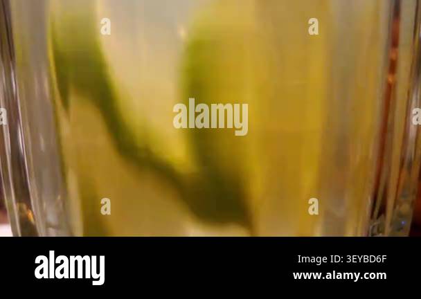 Transparent glass filled with yellow liquid and a slice of lime ...
