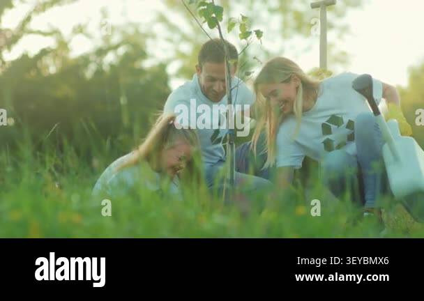 caucasian family planting tree in meadow, parents and young daughter ...