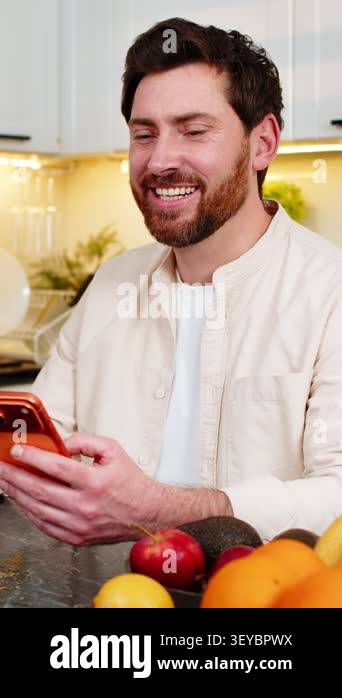 Middle-aged man smiling typing message on smartphone while drinking ...