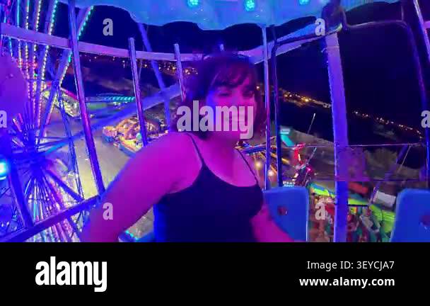 Happy young woman laughing and enjoying a fun ride on a colorful ferris ...