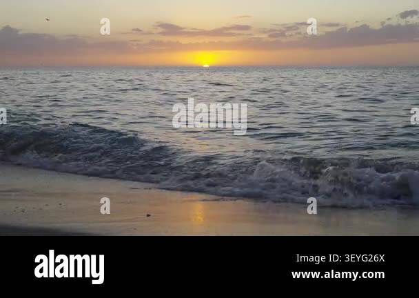 Calm seashore at twilight with soft waves, colorful sky reflections and ...
