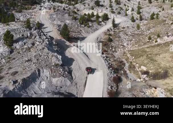 Aerial shot of ATV riders exploring rough rocky terrain from above in a ...