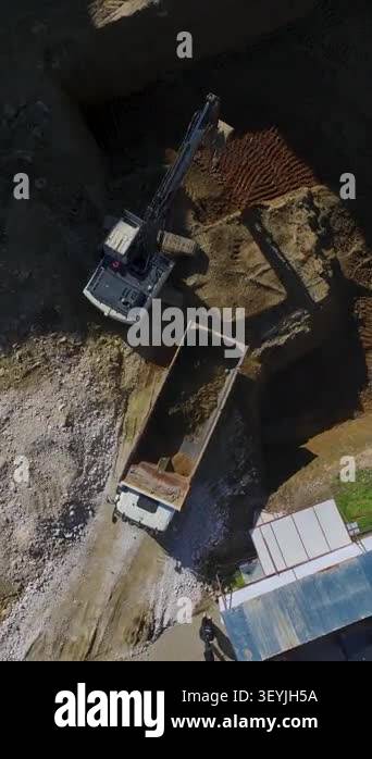 Detailed top angle of excavator bucket releasing heavy soil into a ...