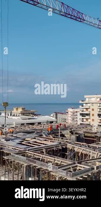 Crane moves heavy materials above residential buildings with mountains ...