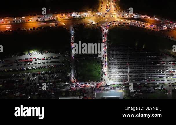 Aerial night view of light trails and parked cars at a busy urban ...