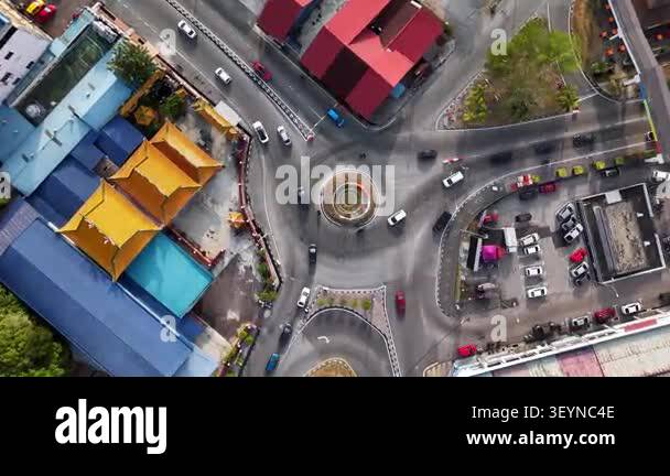 Aerial view of a roundabout with steady traffic flow. Buildings with ...