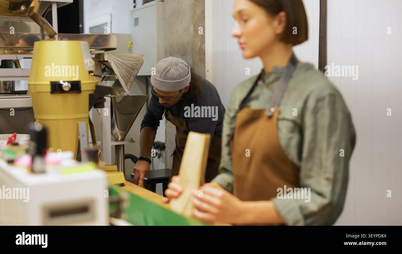 Female worker packing package with coffee beans near male colleague ...