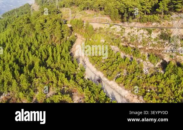 Drone view of buggy moving along dirt road in forest landscape Stock ...