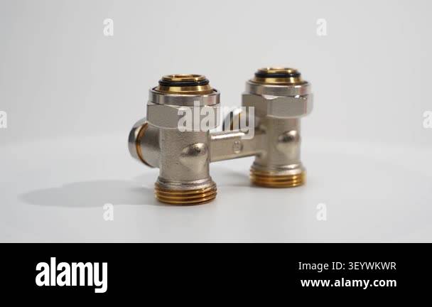 Metal radiator valve fittings rotate against a white background. The ...