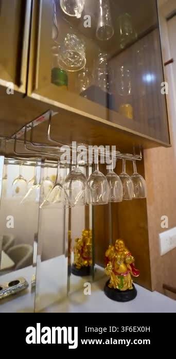 A stylish home bar cabinet featuring hanging wine glasses and ...