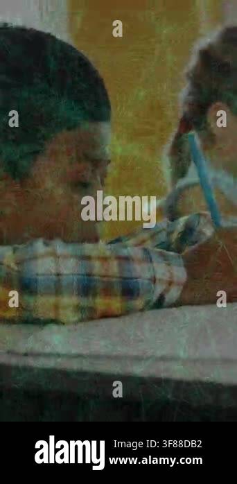 Vertical video: Boy lifting head and moving arm, writing on desk with ...
