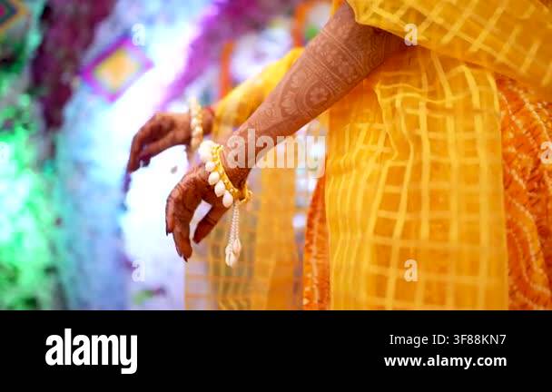 A person wears intricate henna patterns and floral bracelets during a ...