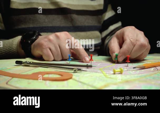Hands of a person with a watch adjust colorful push pins on a detailed ...