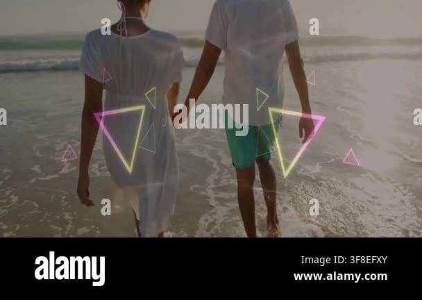 Couple walking ocean shore, stepping into water and causing neon ...