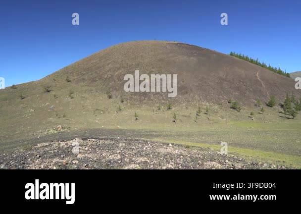 Basalt volcanic hill rises above open grassland, showing tuff and ...