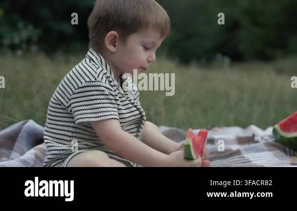Adorable small kid eating sweet juicy watermelon outside on summer day ...