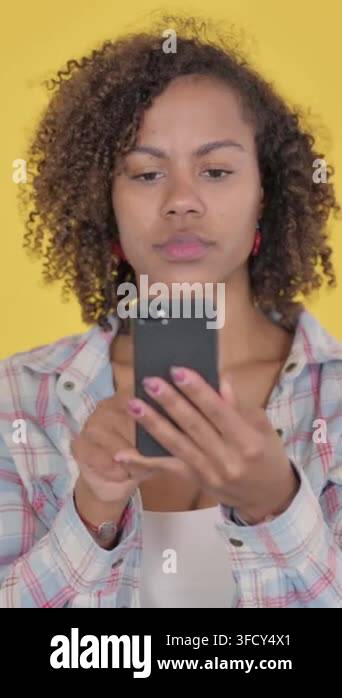 Young African Woman Browsing Smartphone on Yellow Background, Vertical ...