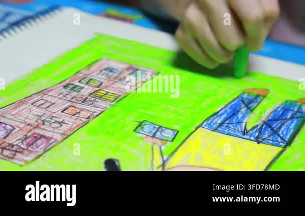 Close up view of a child using a green crayon to color a drawing on a ...